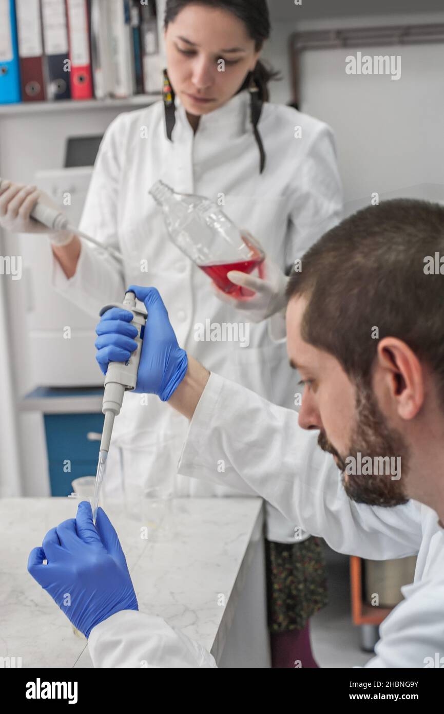 Two scientists in the laboratory filling test tubes with pipette. Close ...