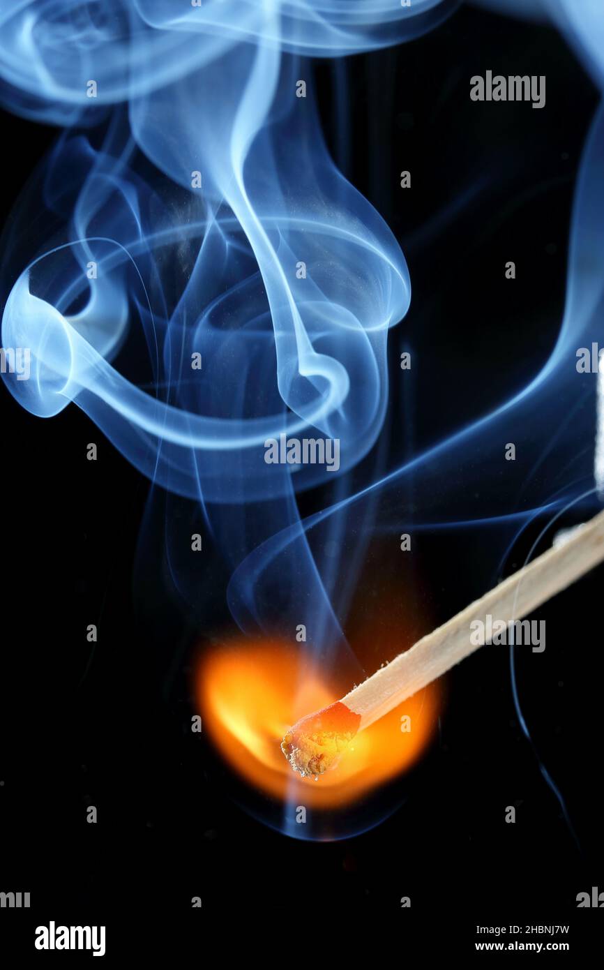 A vertical shot of smoke of a burned cigarette on the dark background ...