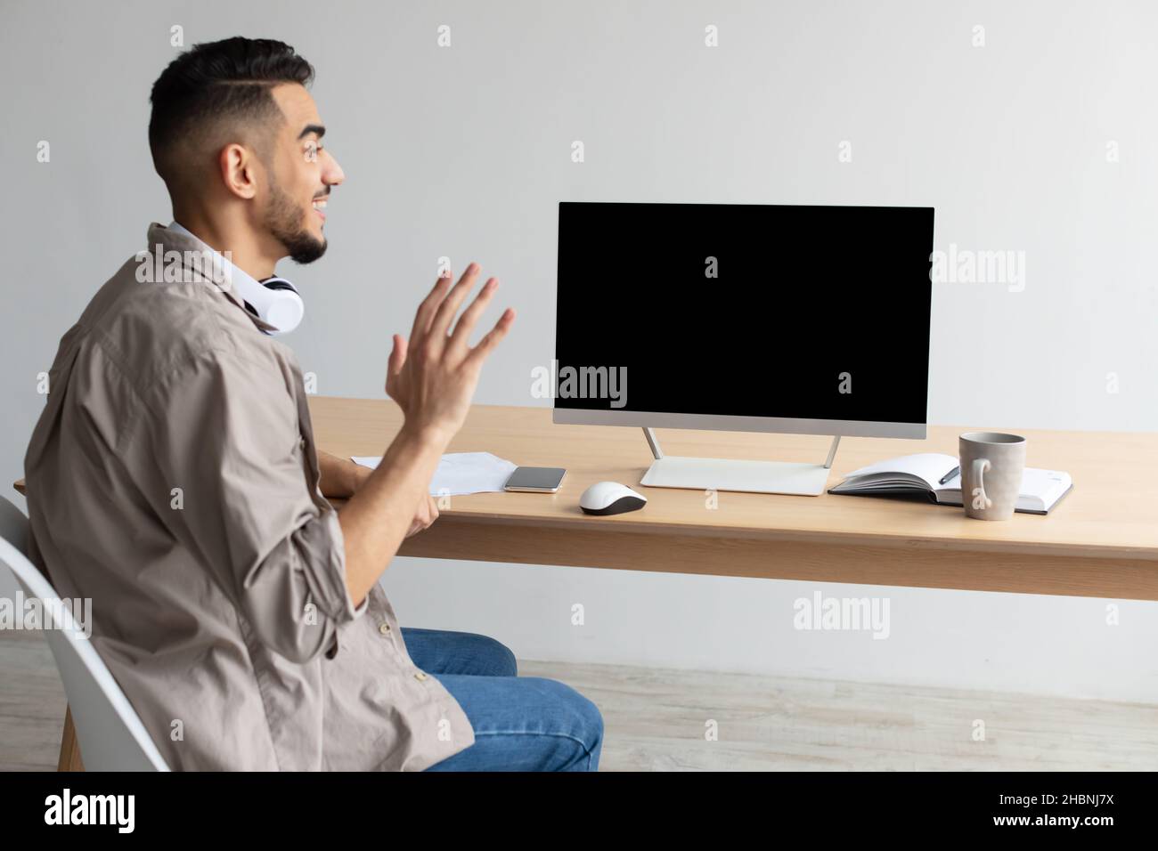 Arab man waving hand at blank empty computer monitor Stock Photo - Alamy