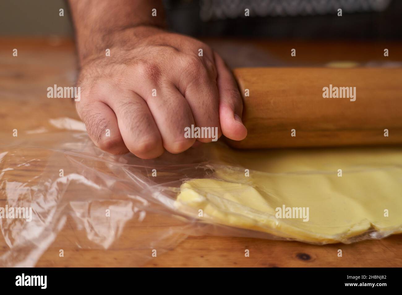 Man with rolling pin stretches butter for preparation with fat inside a ...