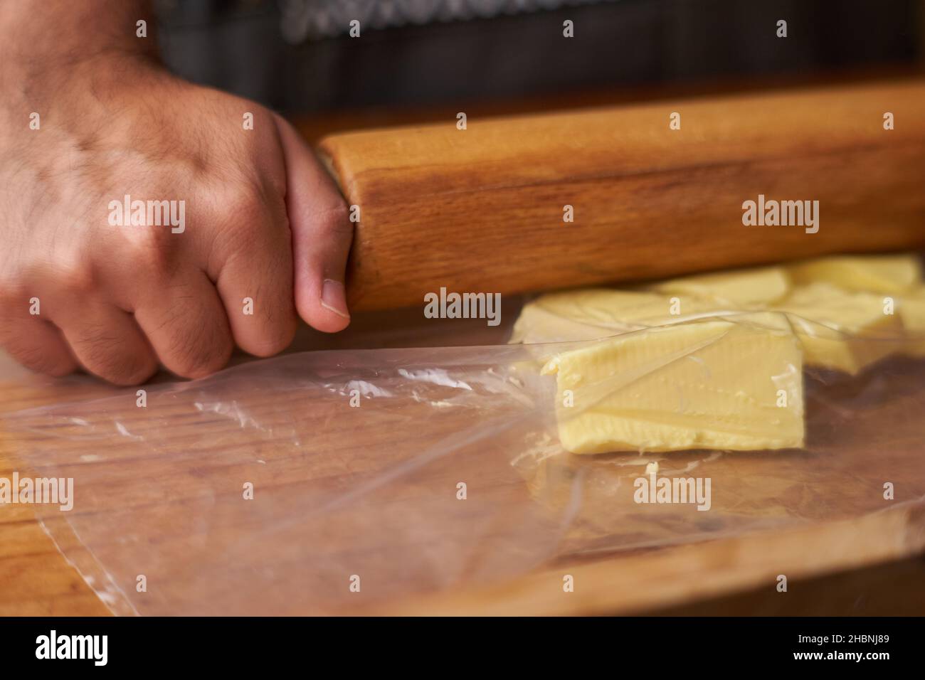 Man with rolling pin stretches butter for preparation with fat. smelly ...