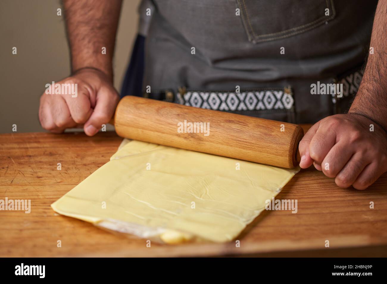 butter filling. Man with rolling pin flattens grease for cooking Stock ...
