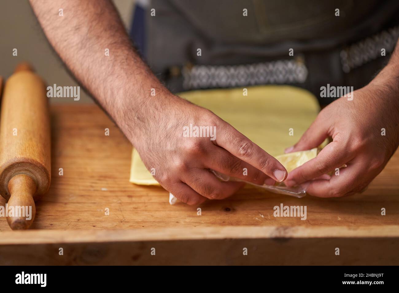 butter filling. Man with rolling pin flattens grease for cooking Stock ...