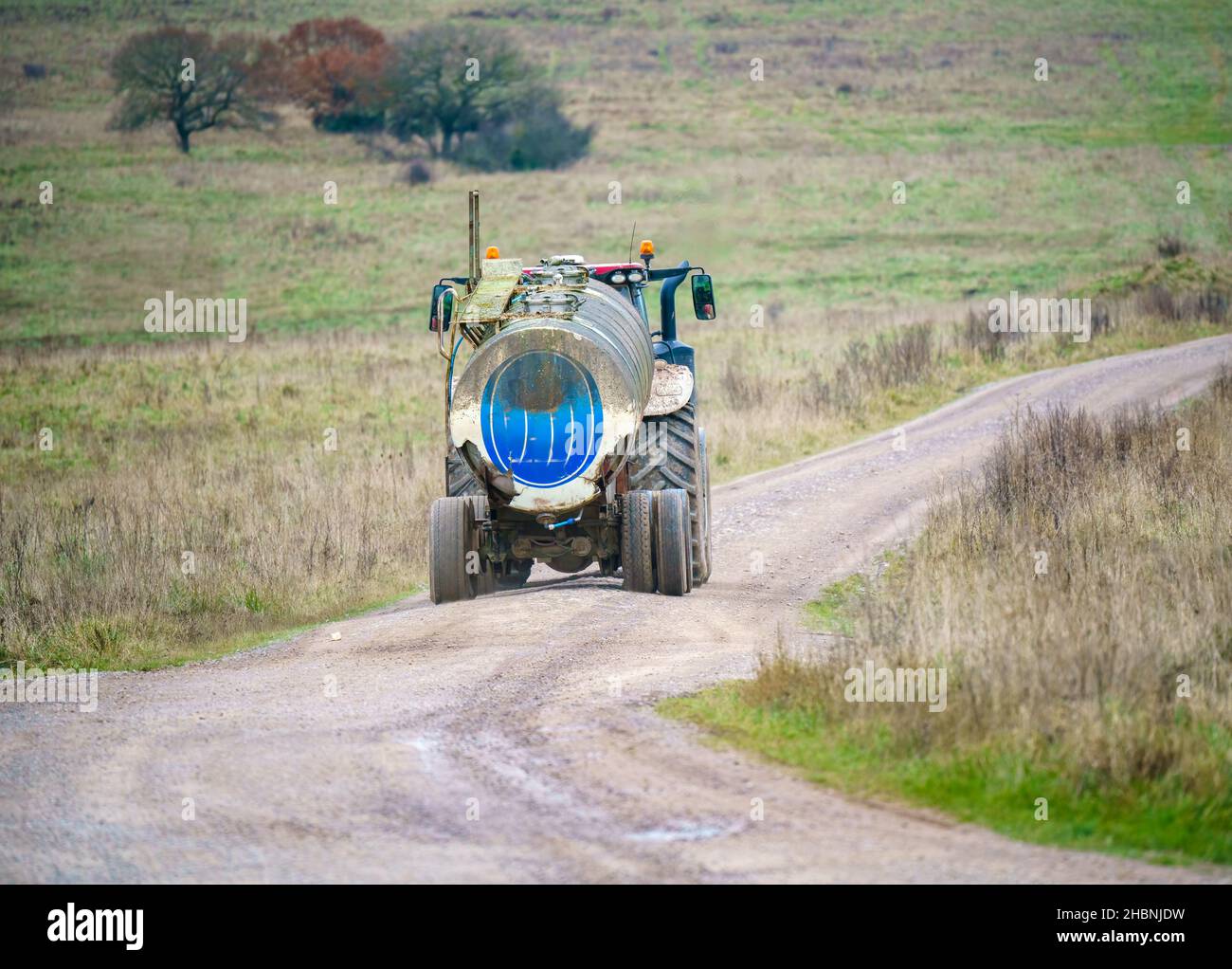tractor towing a 30,000 litre water tanker along a dusty stone track ...