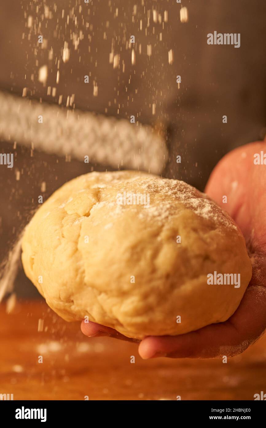 sprinkling flour on a ball of fresh dough. cook sprinkles flour on his ...