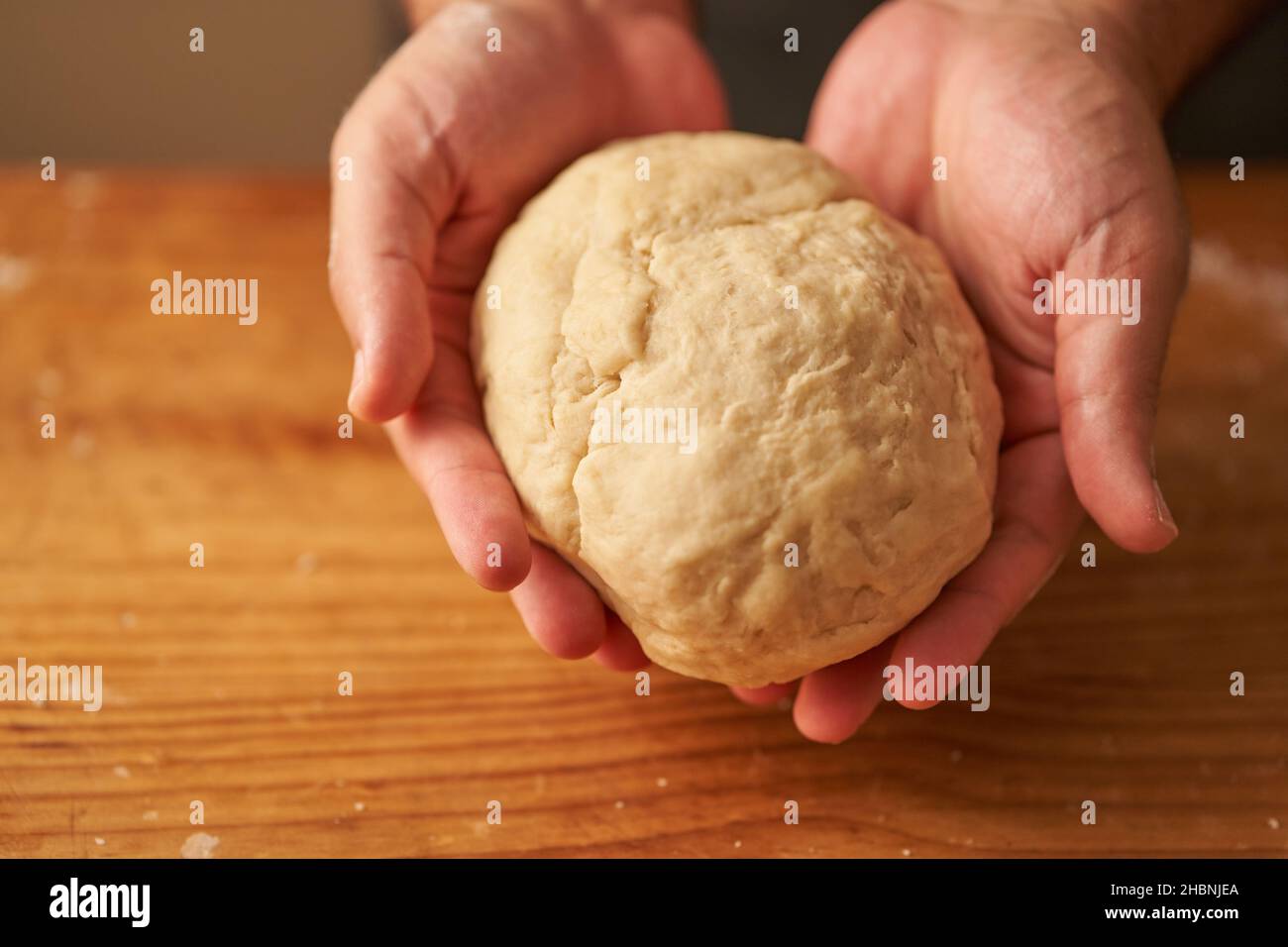 cook's hands hold tender dough before getting its baked preparation ...