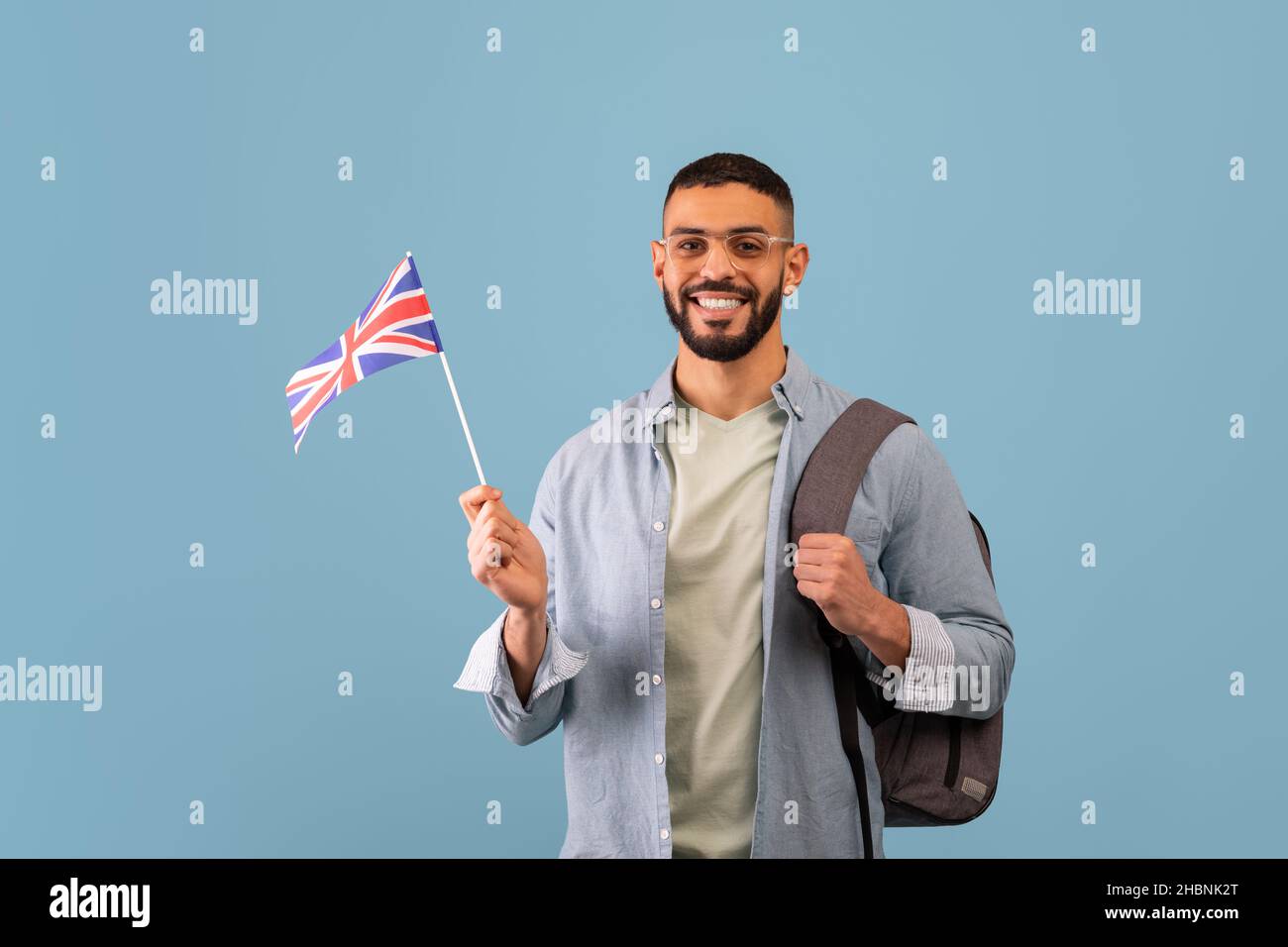 Happy arab guy with backpack showing flag of Great Britain over blue ...