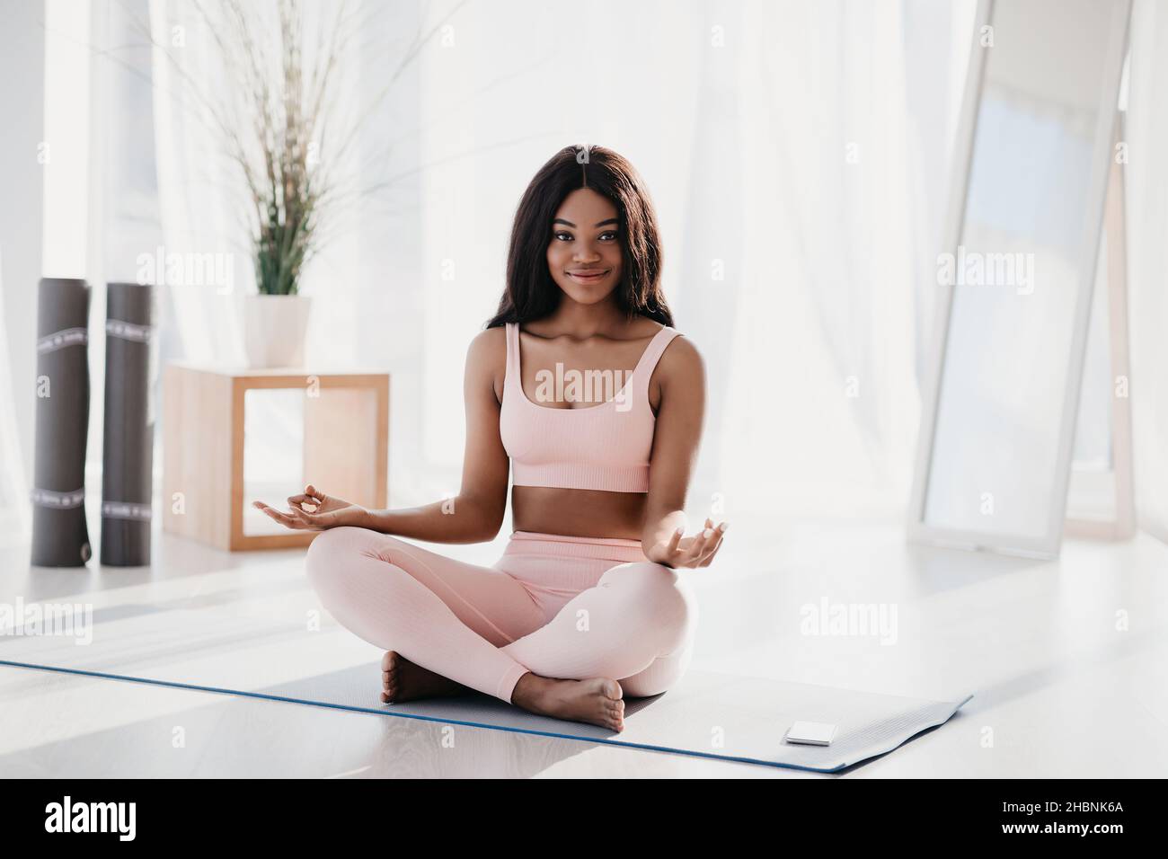 Millennial black lady in sports outfit meditating alone on yoga mat at ...
