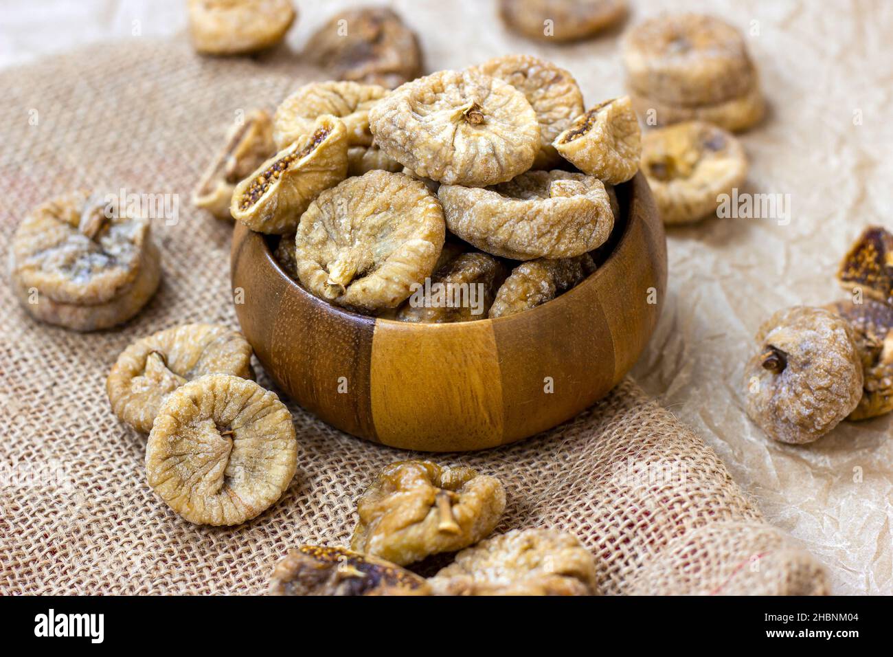 Sweet dried italian figs in the wooden bowl on the brown cutting board ...