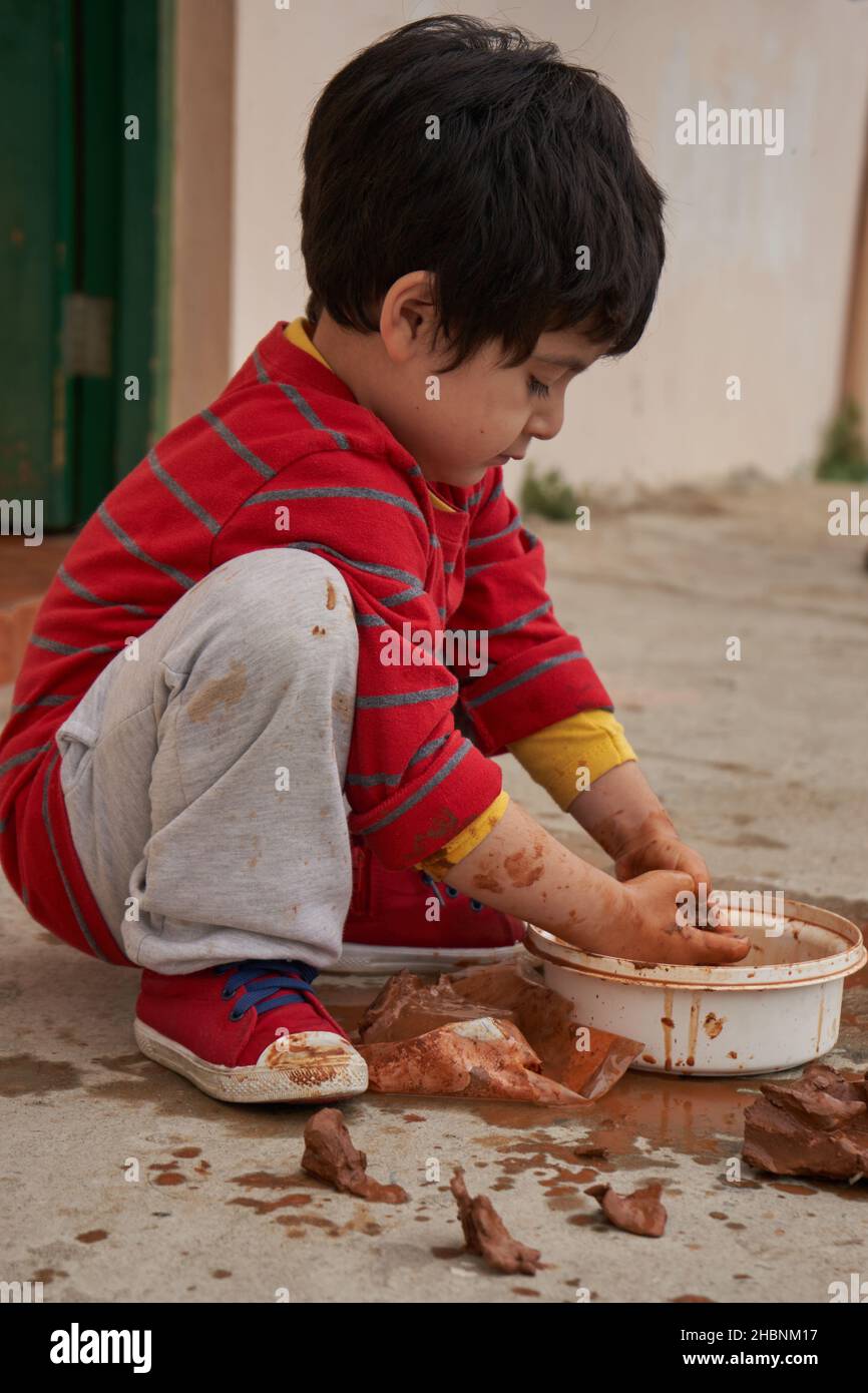 Child kneeling and very concentrated makes figures with clay Stock ...