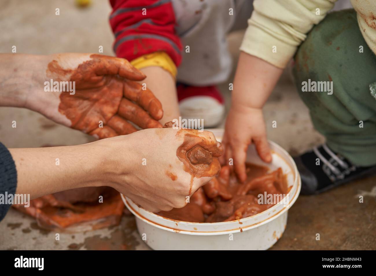 Woman squeezes the clay before molding figures together with children ...