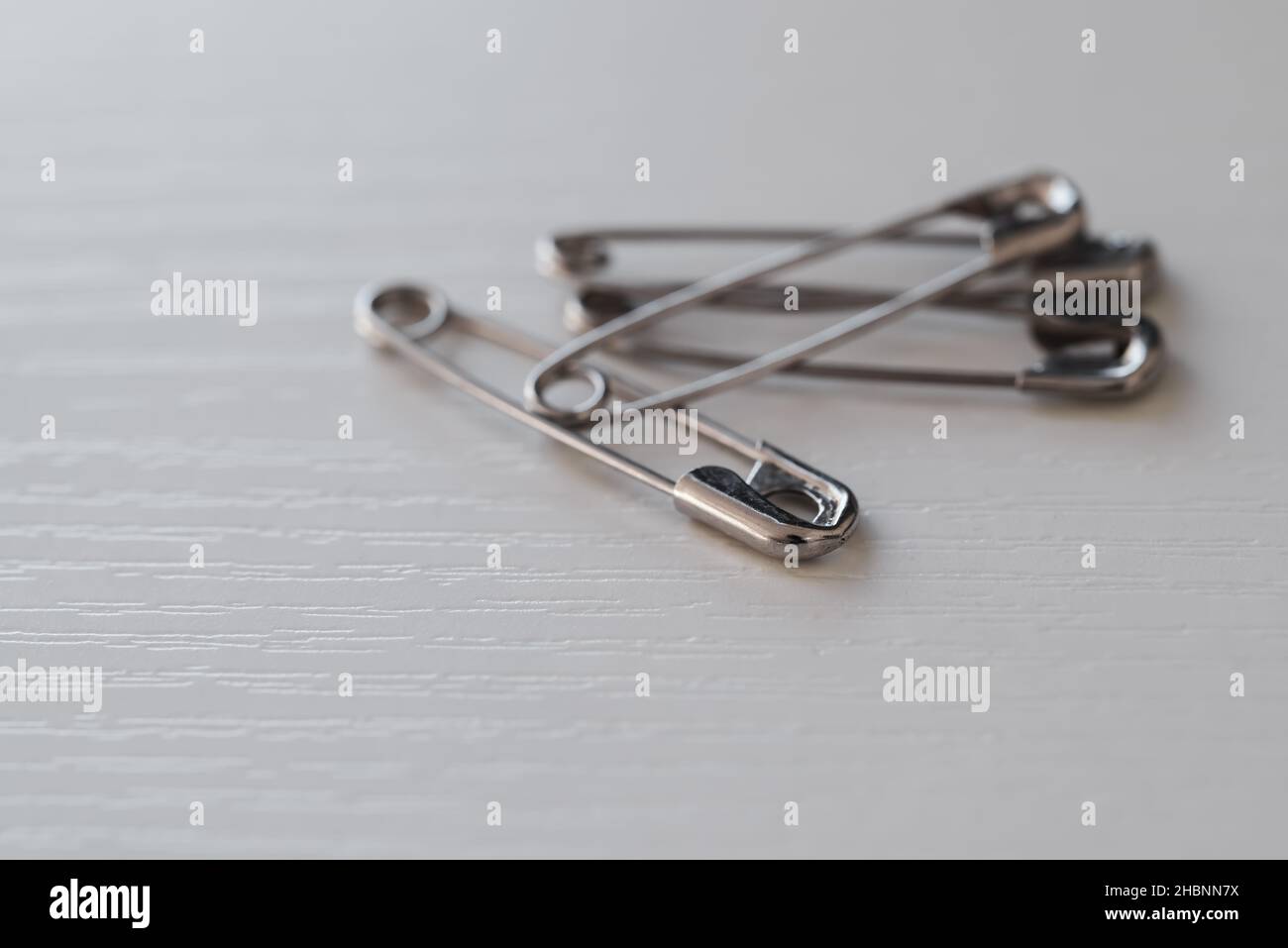 closeup of a pile of four metal safety pins on a white desk Stock Photo ...