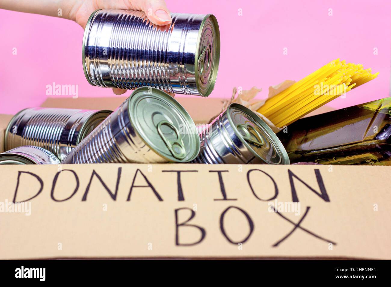 Donation carton box with food (pasta, cans, beans and other) and hand ...