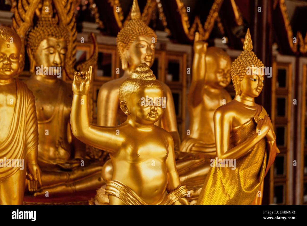 Golden statues of Buddha and a statue of a child pointing index finger ...