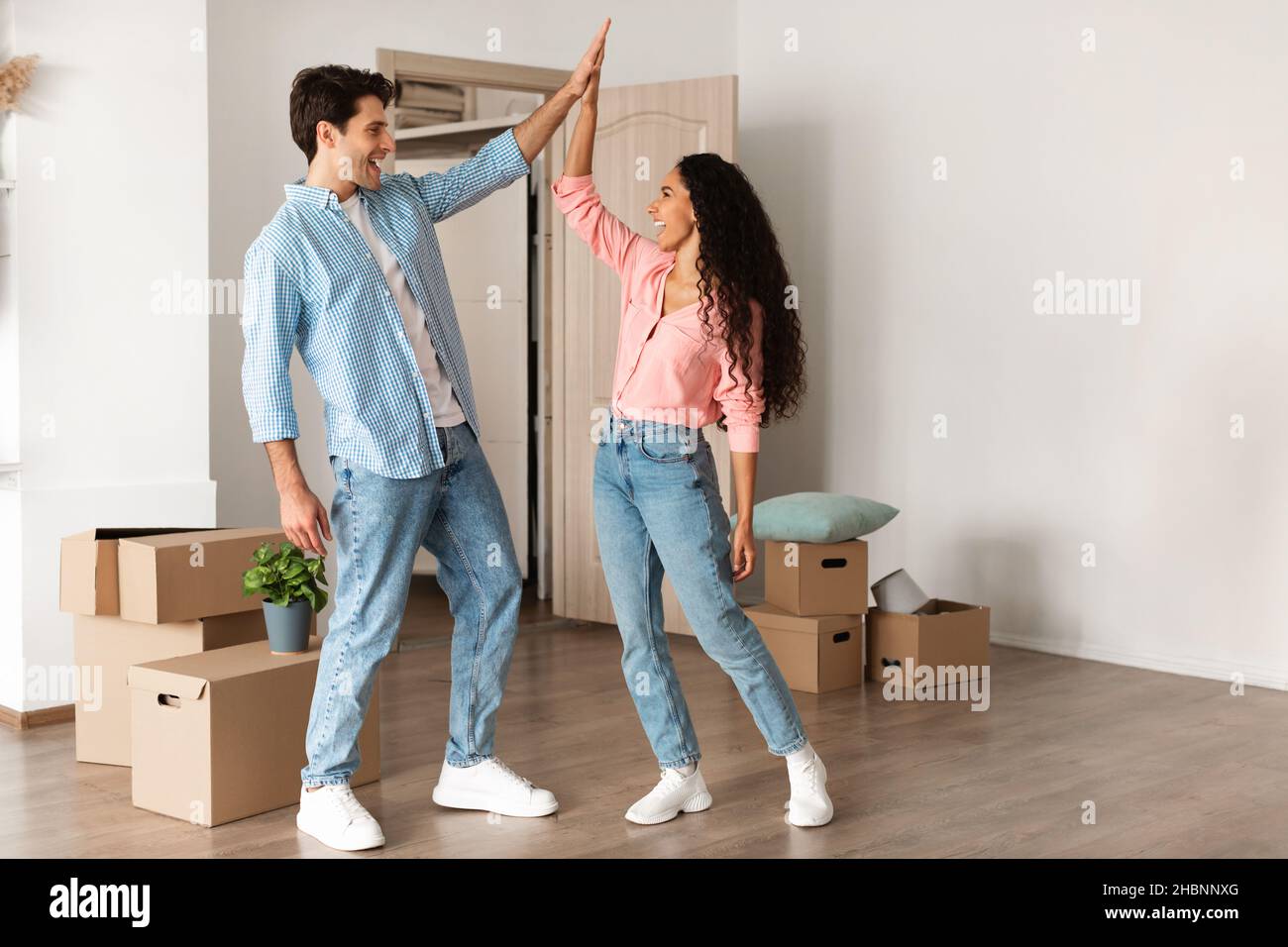 Happy man and woman giving high five celebrating moving day Stock Photo ...
