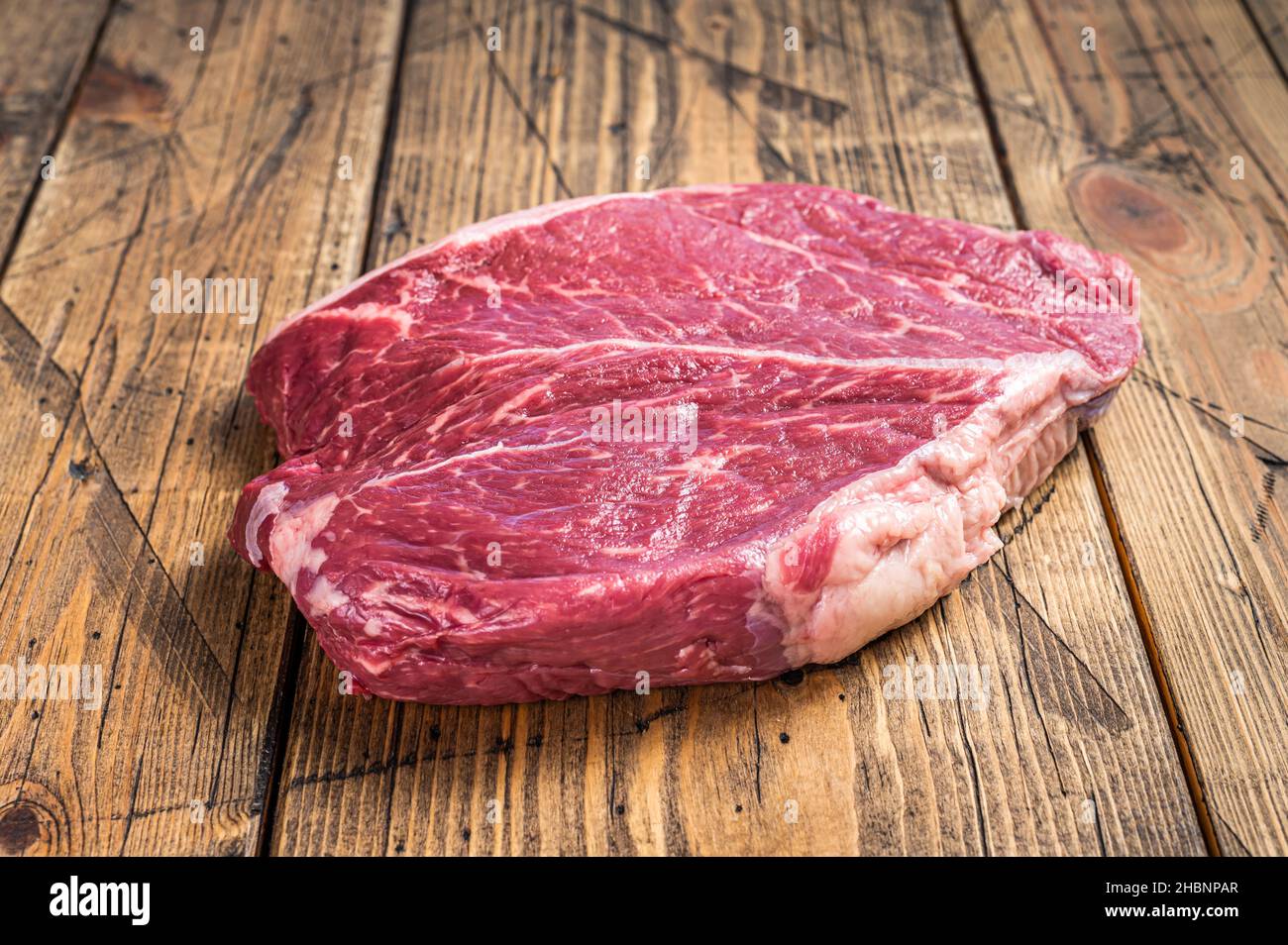 Dry aged raw beef round steak cut on a butcher table. wooden background ...