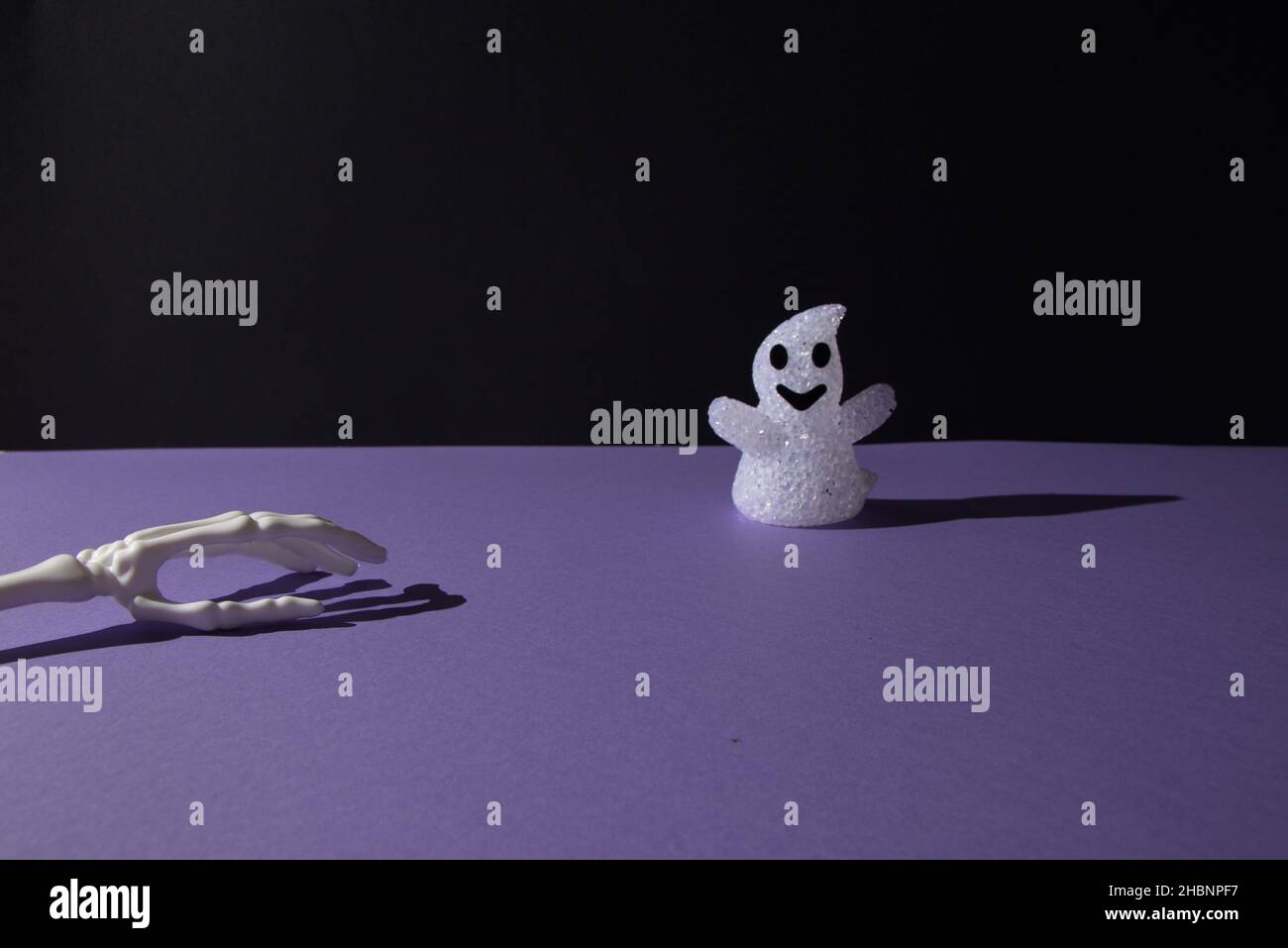 A ghost decoration for Helloween and hand bones on purple black ...