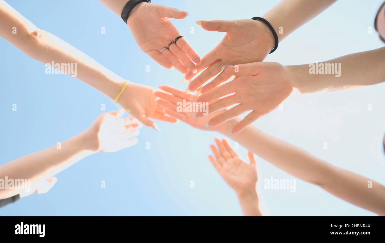 Cheerful girls join hands together as a sign of unity and joint ...