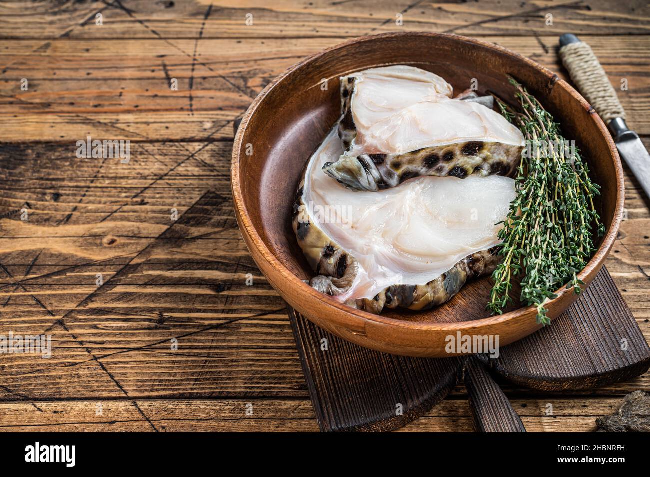 Raw wolffish or wolf fish fillet in a wooden plate. wooden background ...