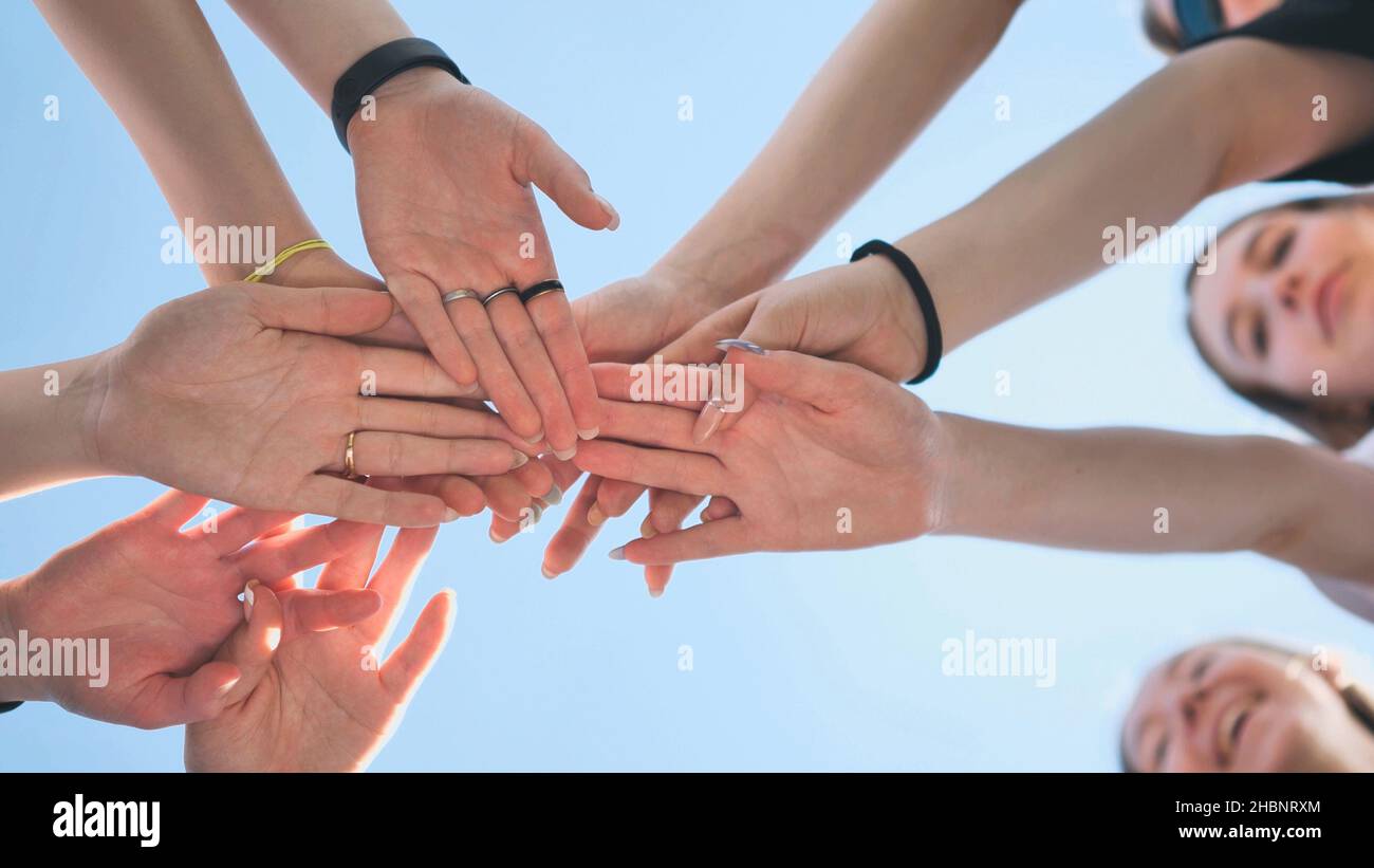 Cheerful girls join hands together as a sign of unity and joint ...