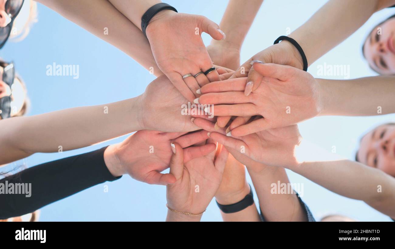 Cheerful girls join hands together as a sign of unity and joint ...