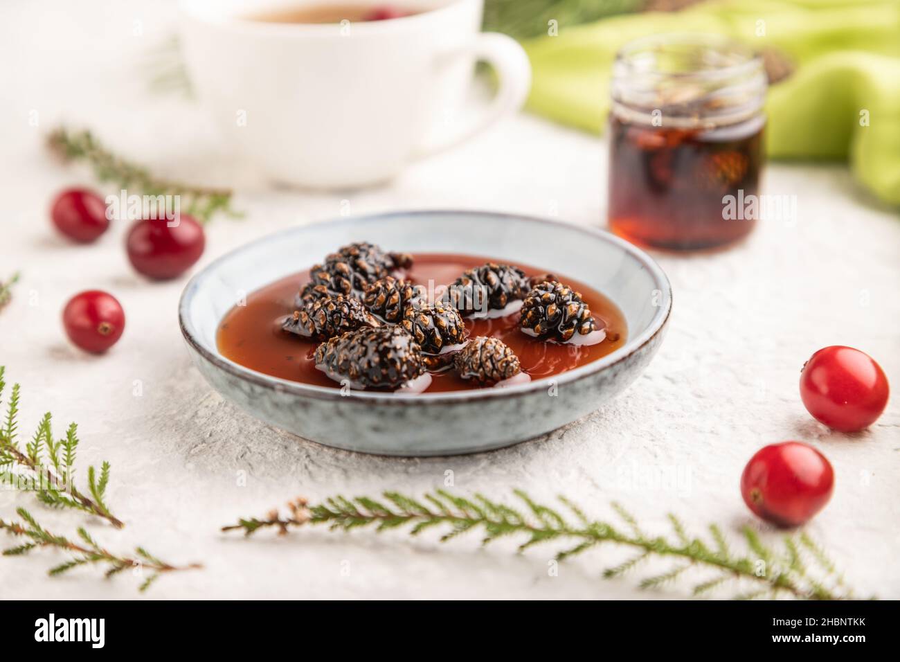 Pine cone jam with herbal tea on gray concrete background and green ...