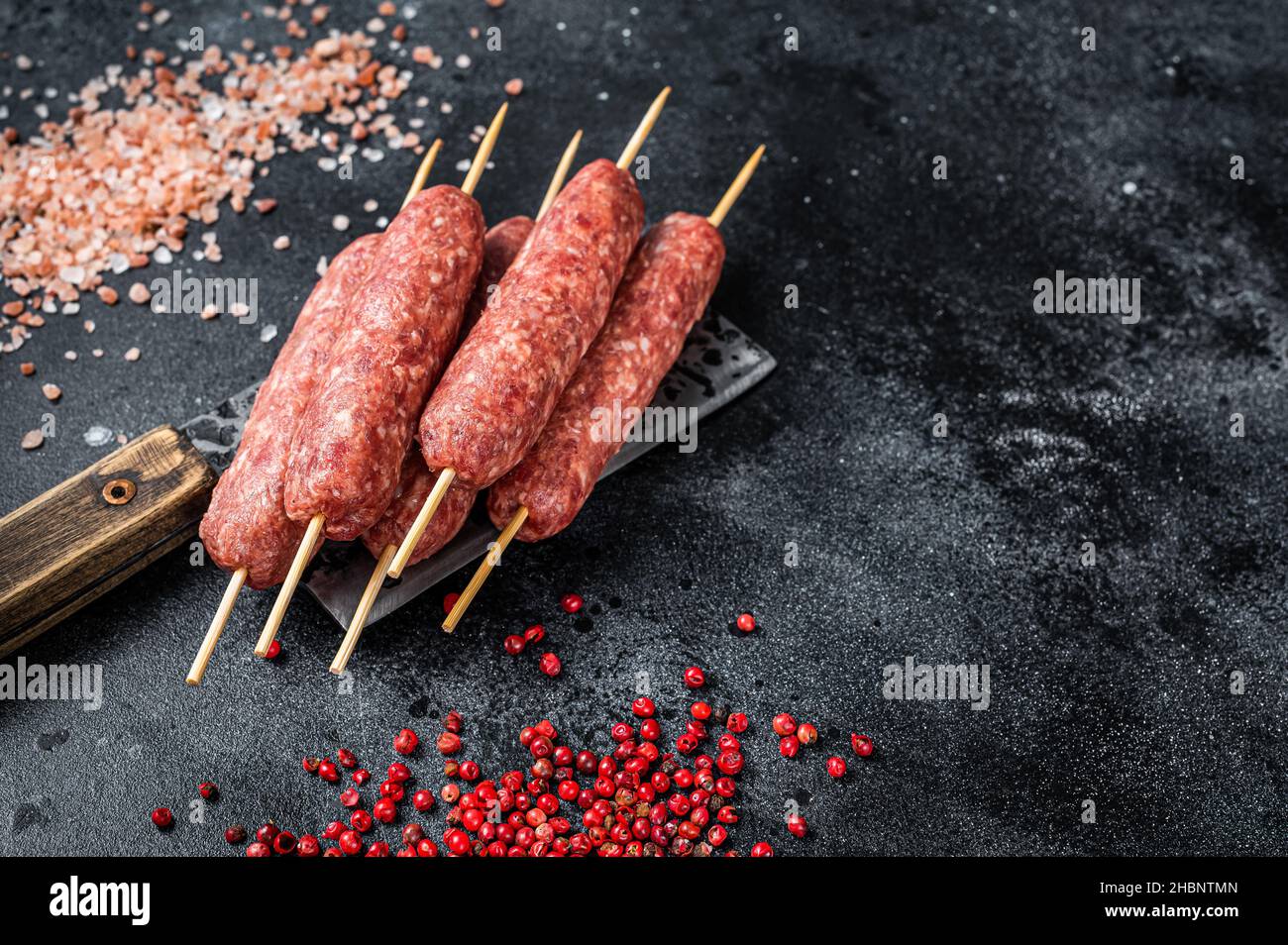 Raw lula or kofta kebabs skewers on a butcher cleaver with salt and ...