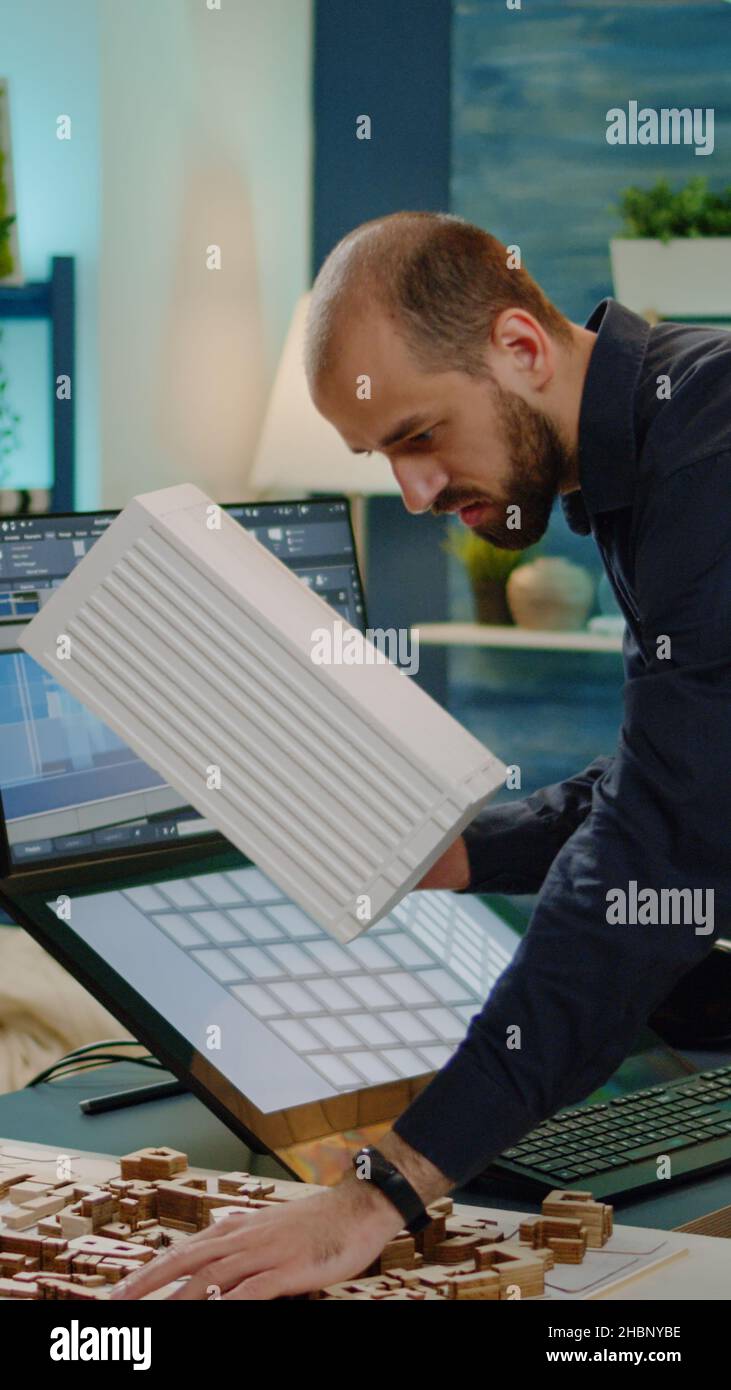 Young engineer holding maquette model analyzing layout and blueprints ...