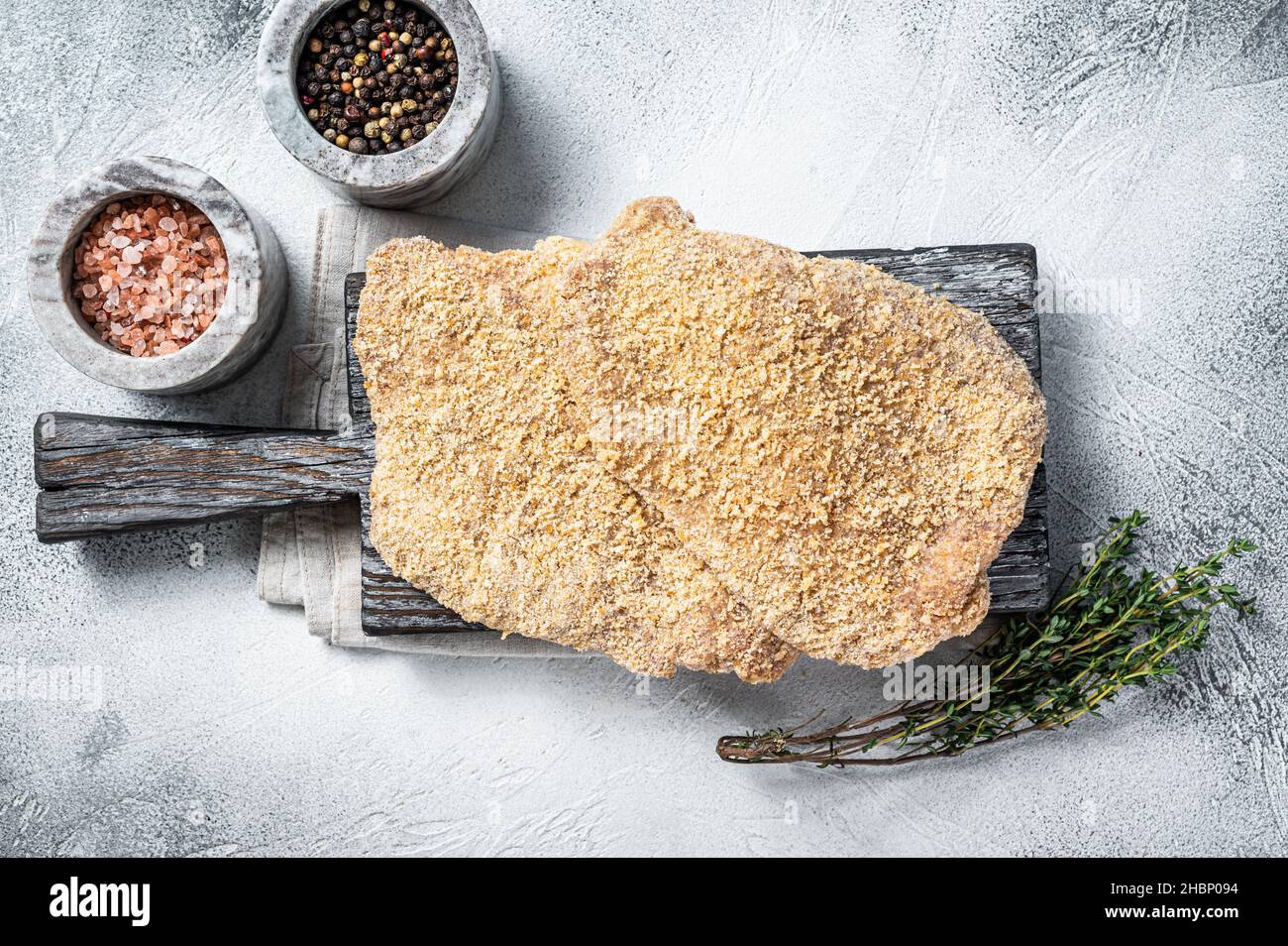 Wiener Raw schnitzel in breadcrumbs on wooden board. White background ...