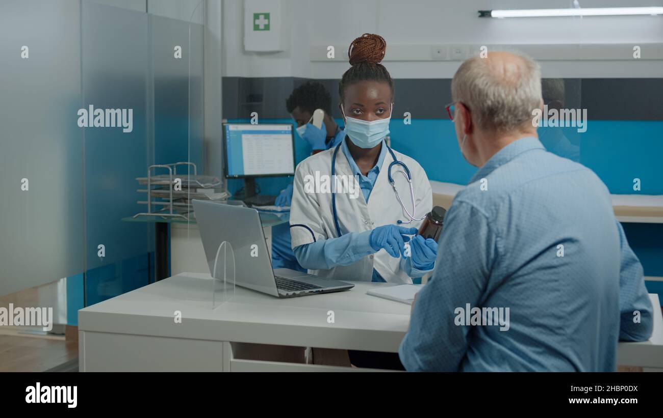 Black professional doctor showing bottle of pills to elder patient ...