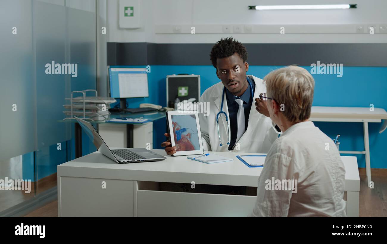 Healthcare specialist explaining cardiogram on tablet display to old ...