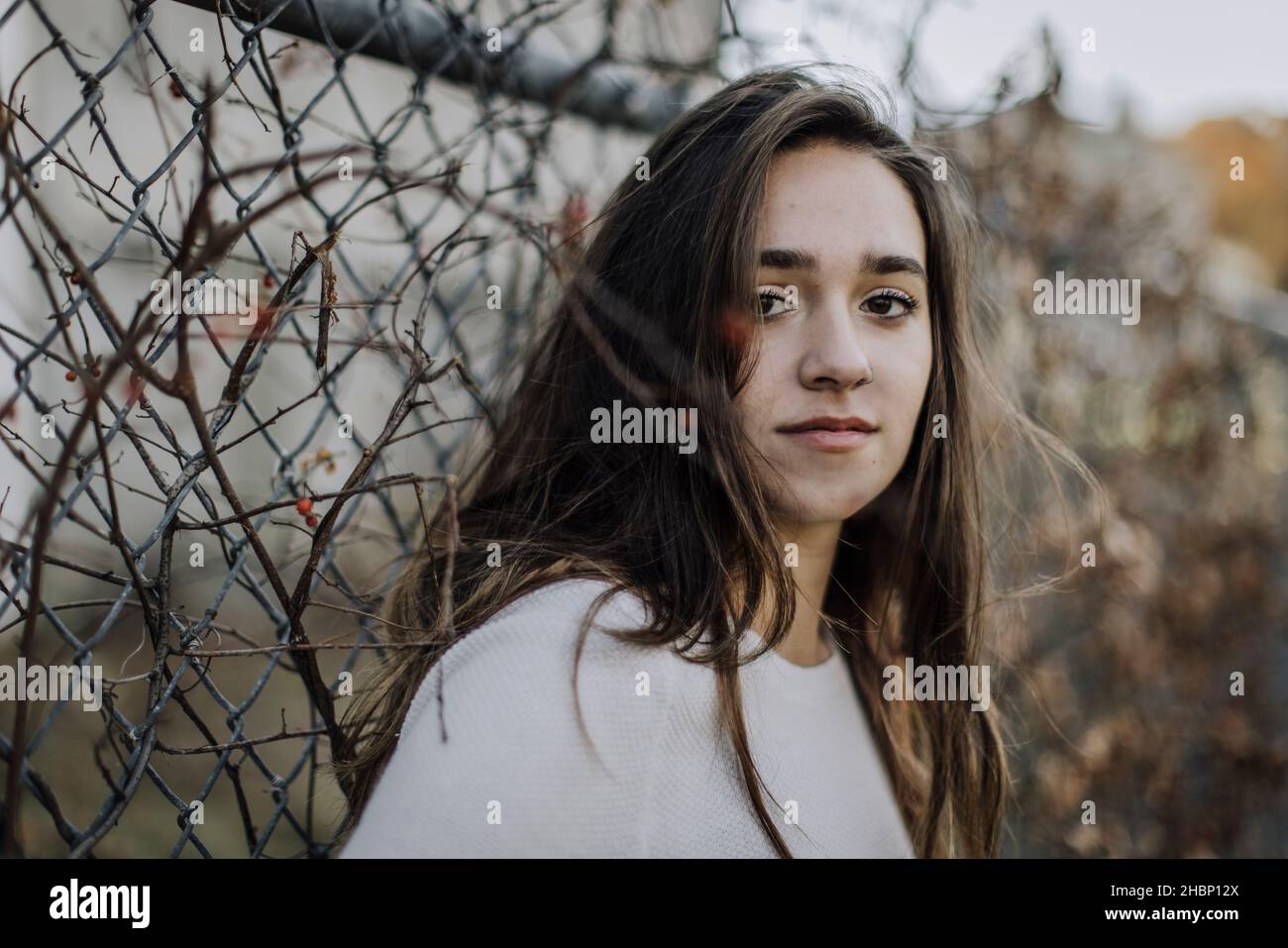 Portrait of teenage girl against chain link fence with vines Stock ...