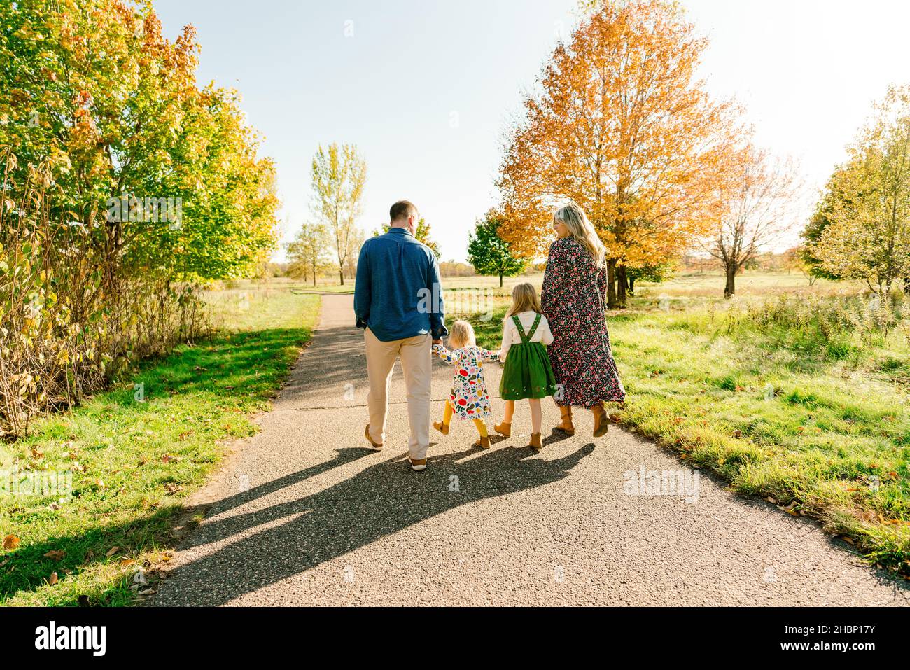 View from behind of a family of four walking on a park path Stock Photo ...