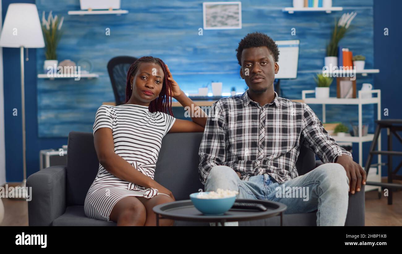 African american couple watching scary movie on TV, sitting on couch ...