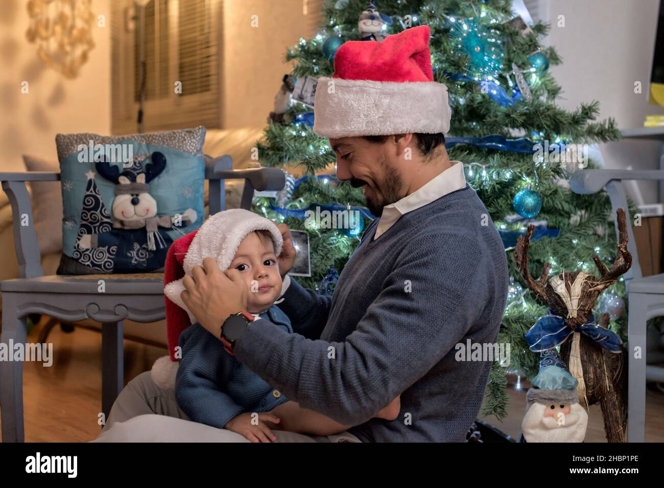 Young latin dad with his son wearing santa claus hats for christmas ...