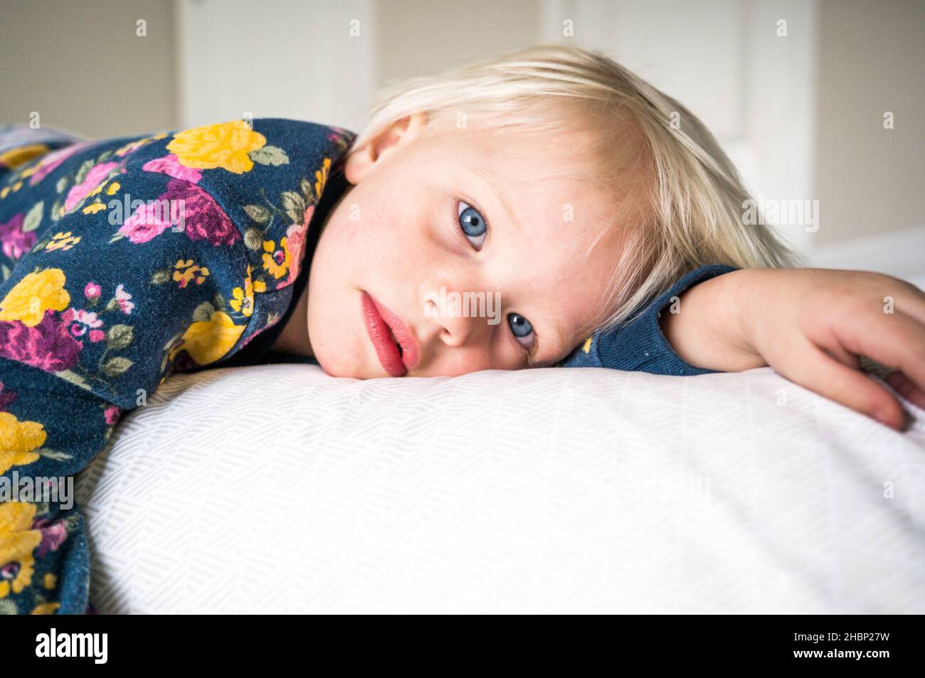 toddler girl laying on her side staring into camera Stock Photo - Alamy
