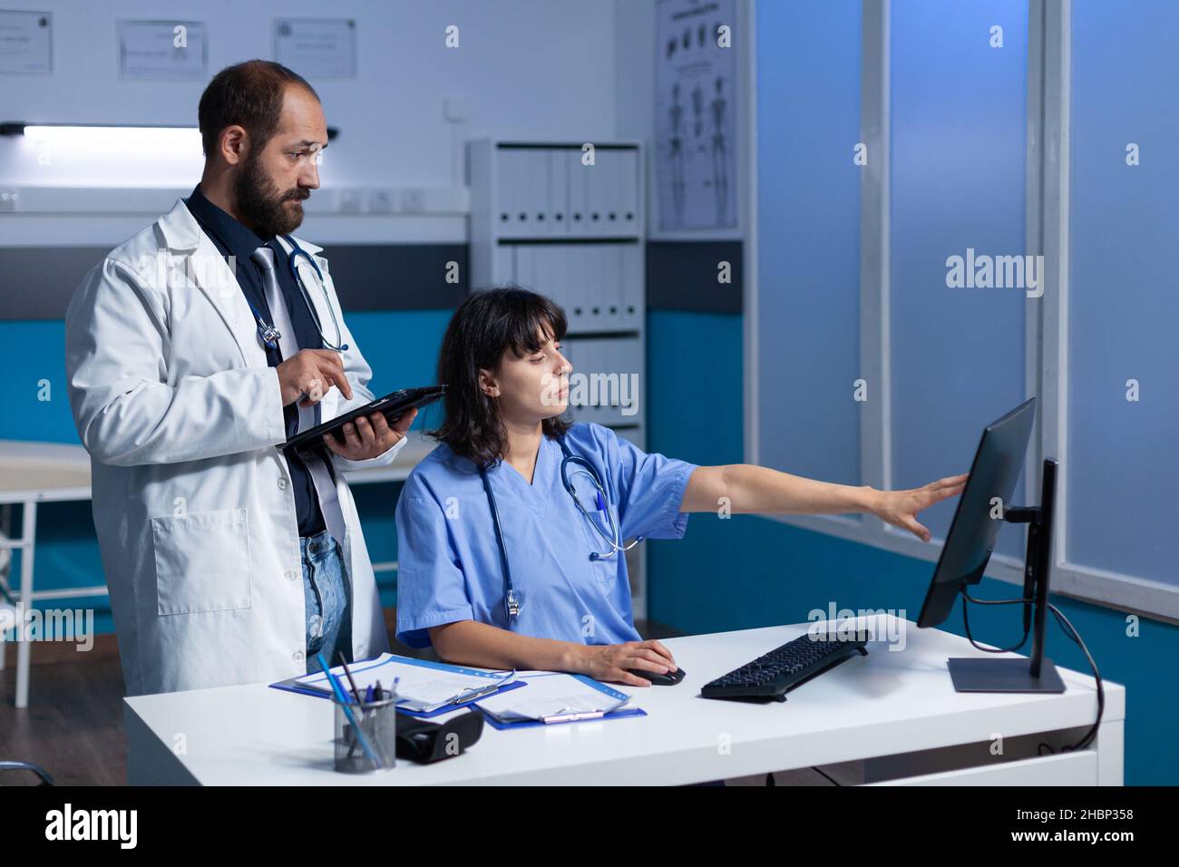Team of medical specialists looking at computer screen and talking ...