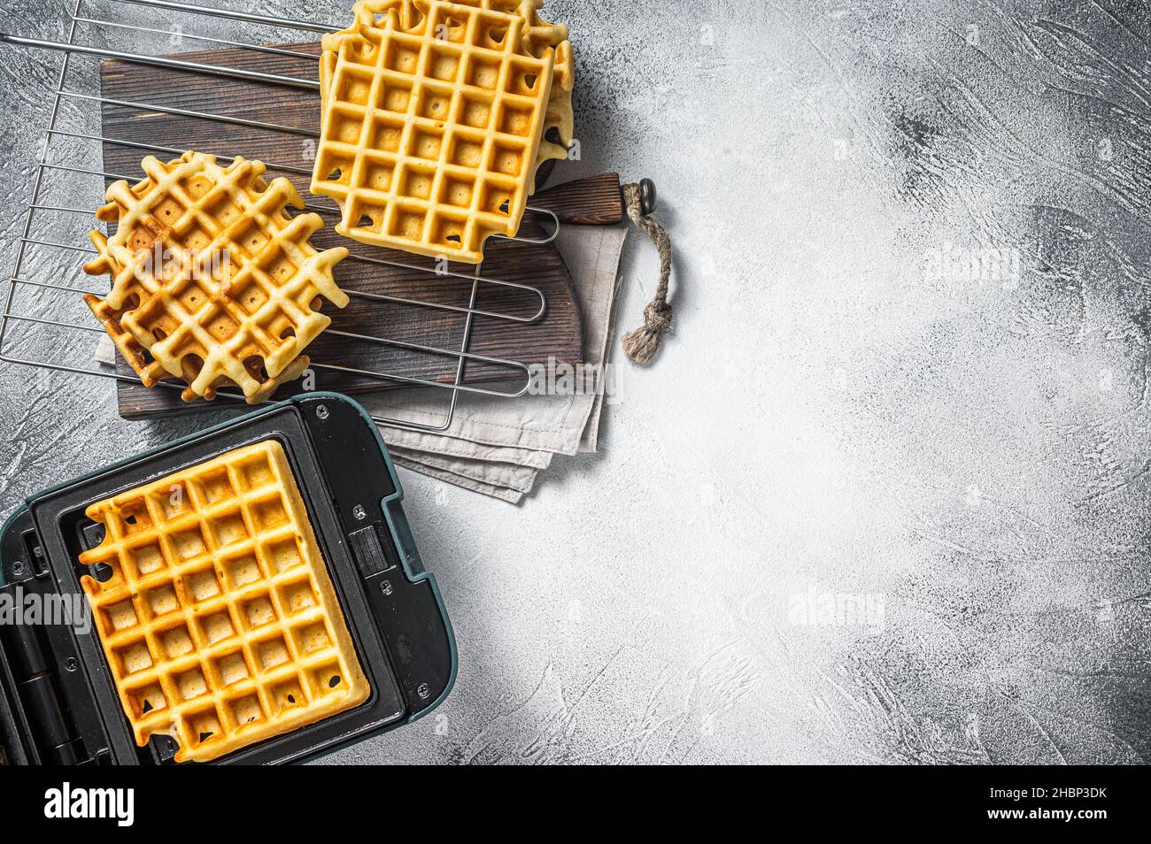Cooking of fresh waffles in waffle maker. White background. Top view ...