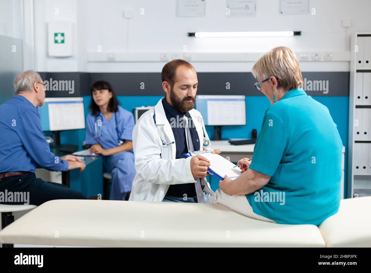 Senior patient signing checkup papers hi-res stock photography and ...