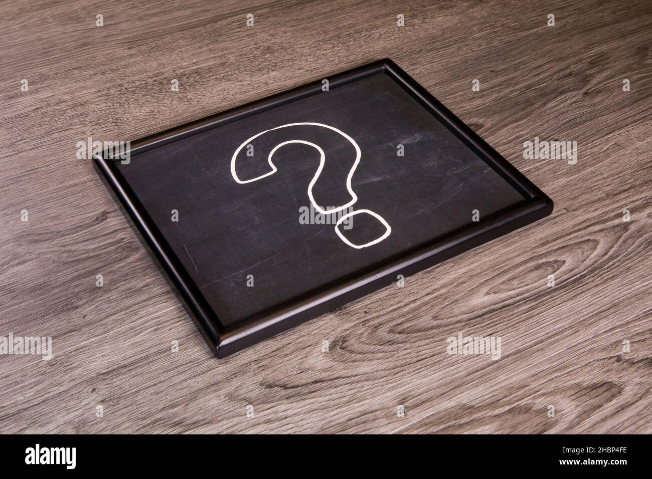 A question mark icon on chalkboard, blackboard over a gray wood ...