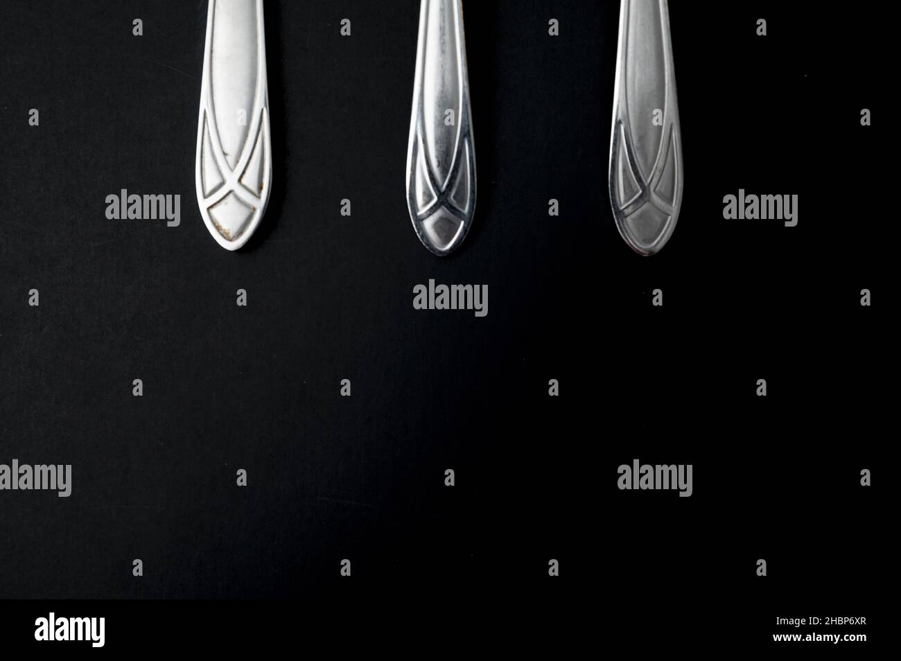 Three silverware handles isolated in the black background with a copy ...