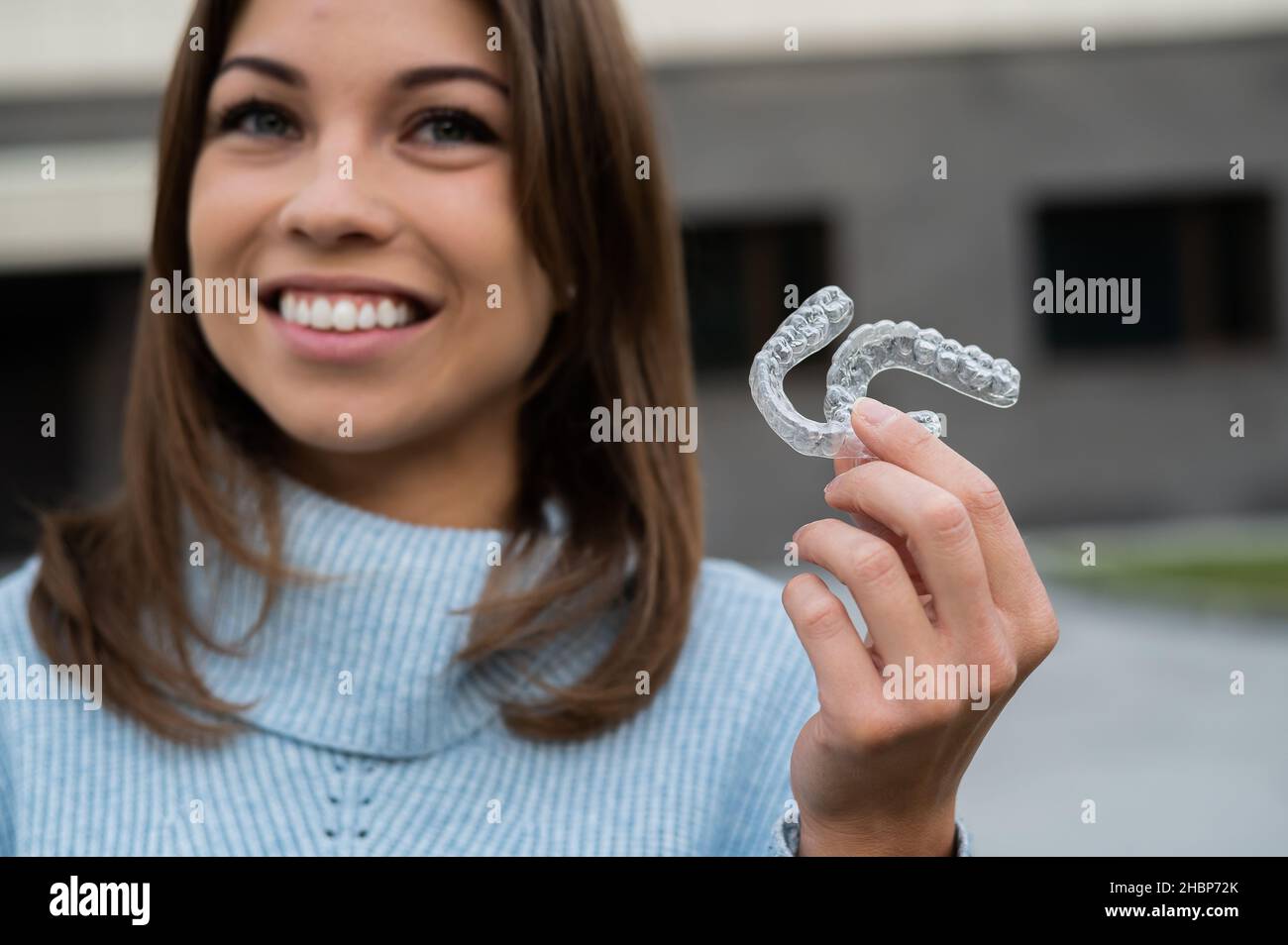 Caucasian woman with white smile holding transparent removable retainer ...