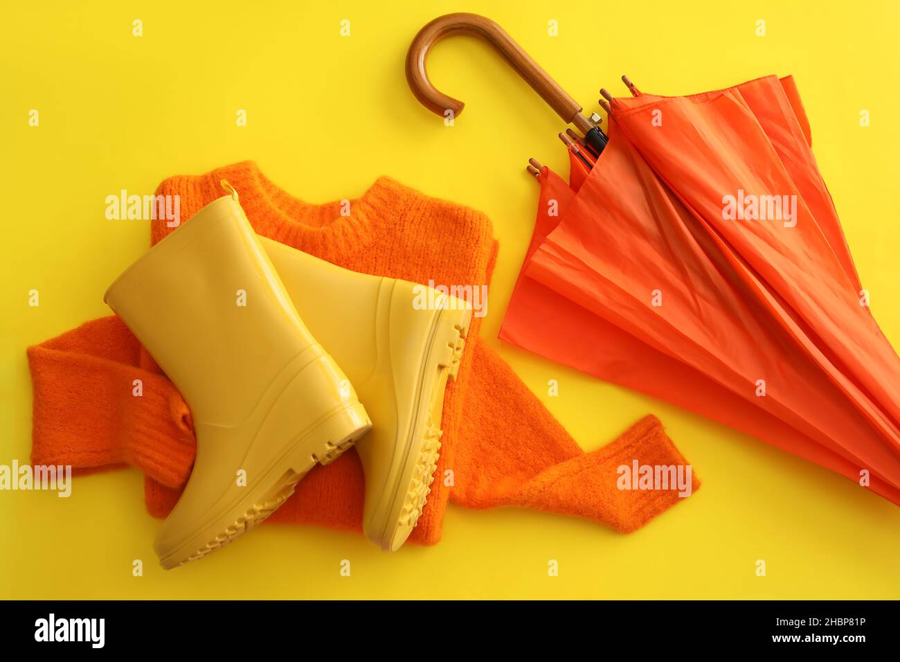Rubber boots, umbrella and sweater on yellow background Stock Photo - Alamy