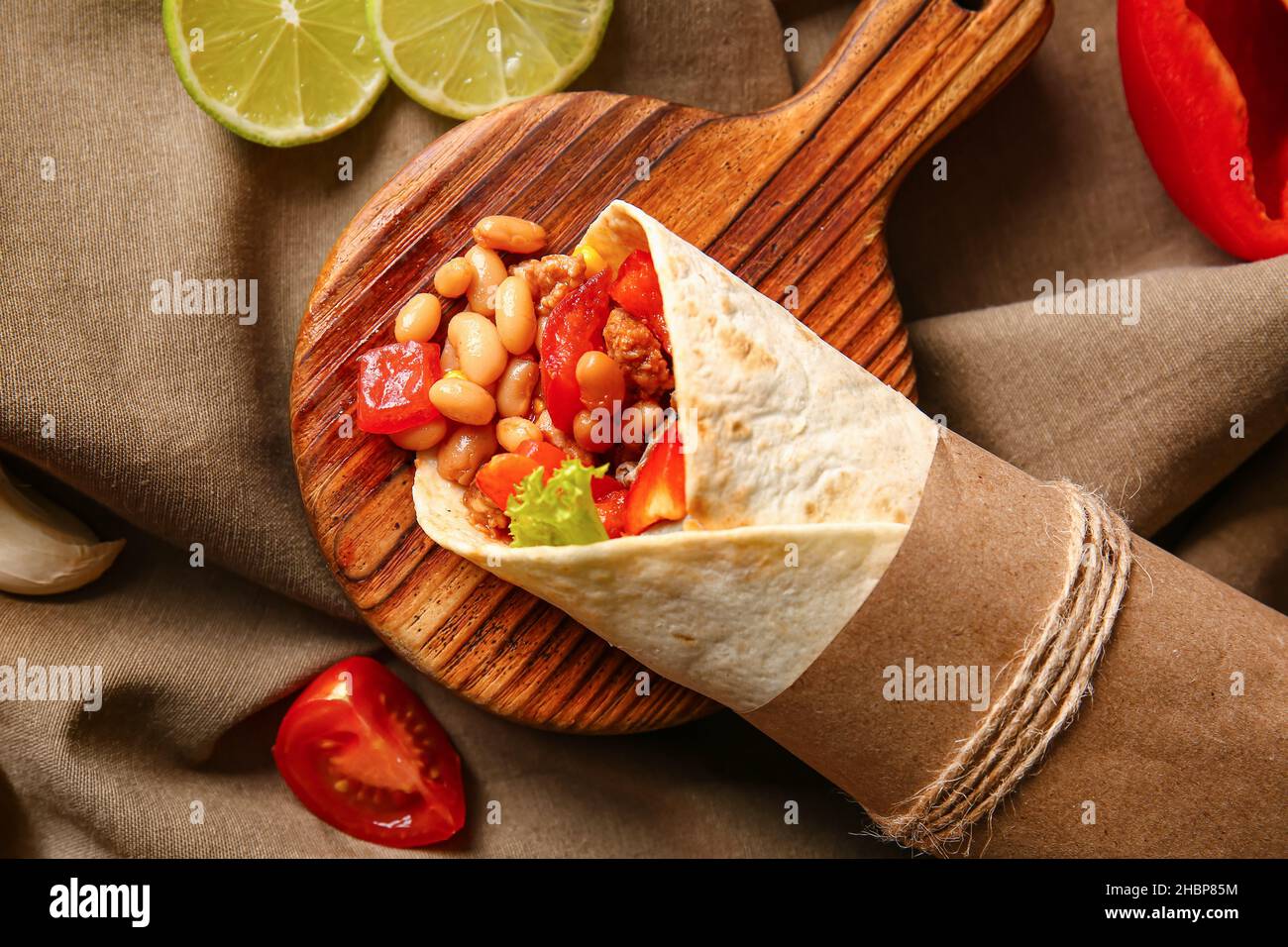 Wooden board of tasty Mexican burrito with vegetables on table Stock ...