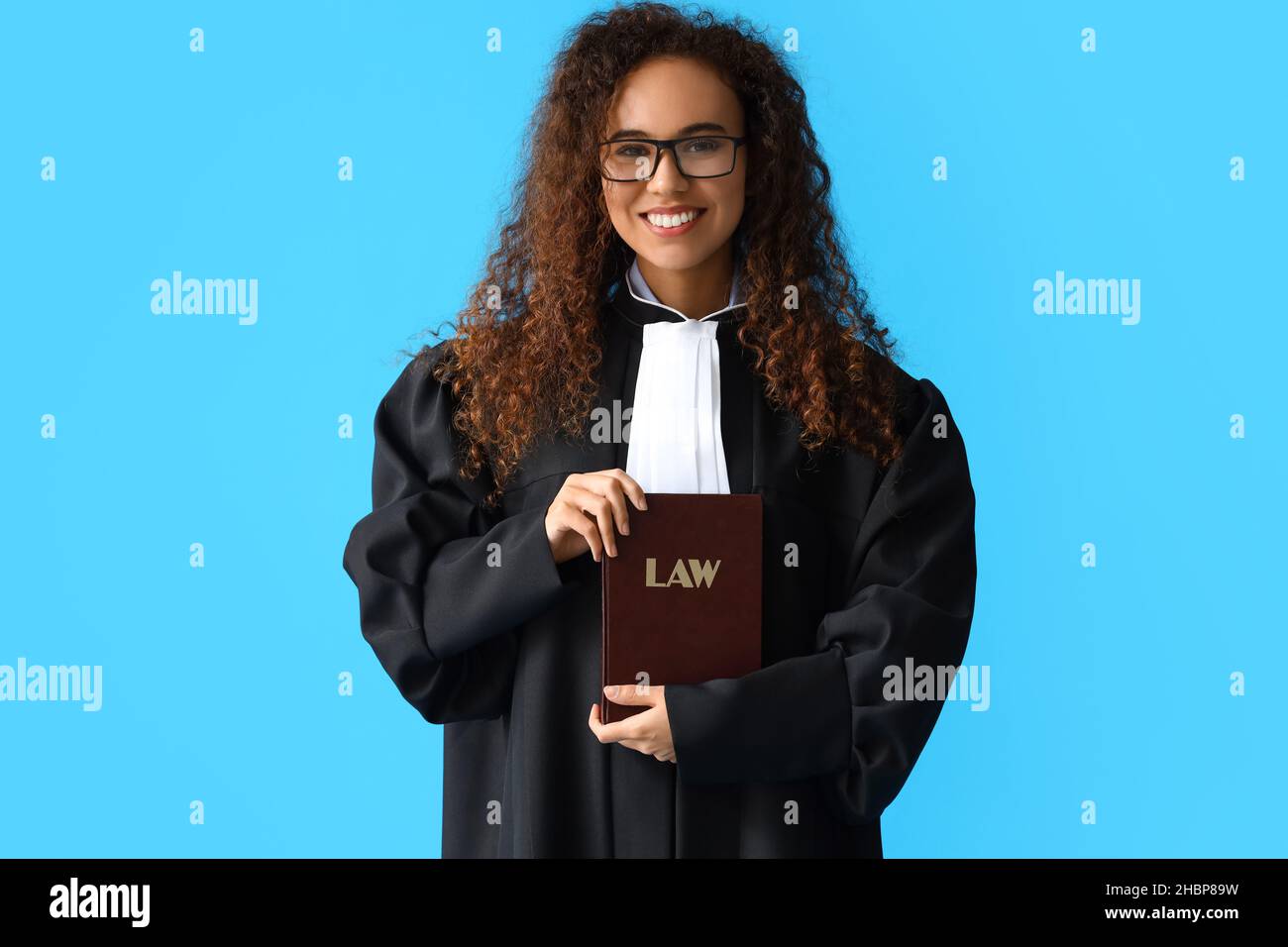 Young female judge with law book on color background Stock Photo - Alamy