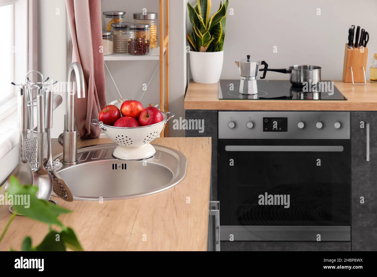 Interior of modern kitchen with wooden counter, silver sink and ...