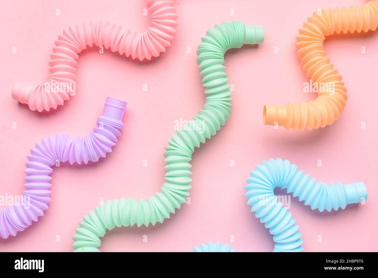 Different colorful Pop Tubes on pink background Stock Photo - Alamy