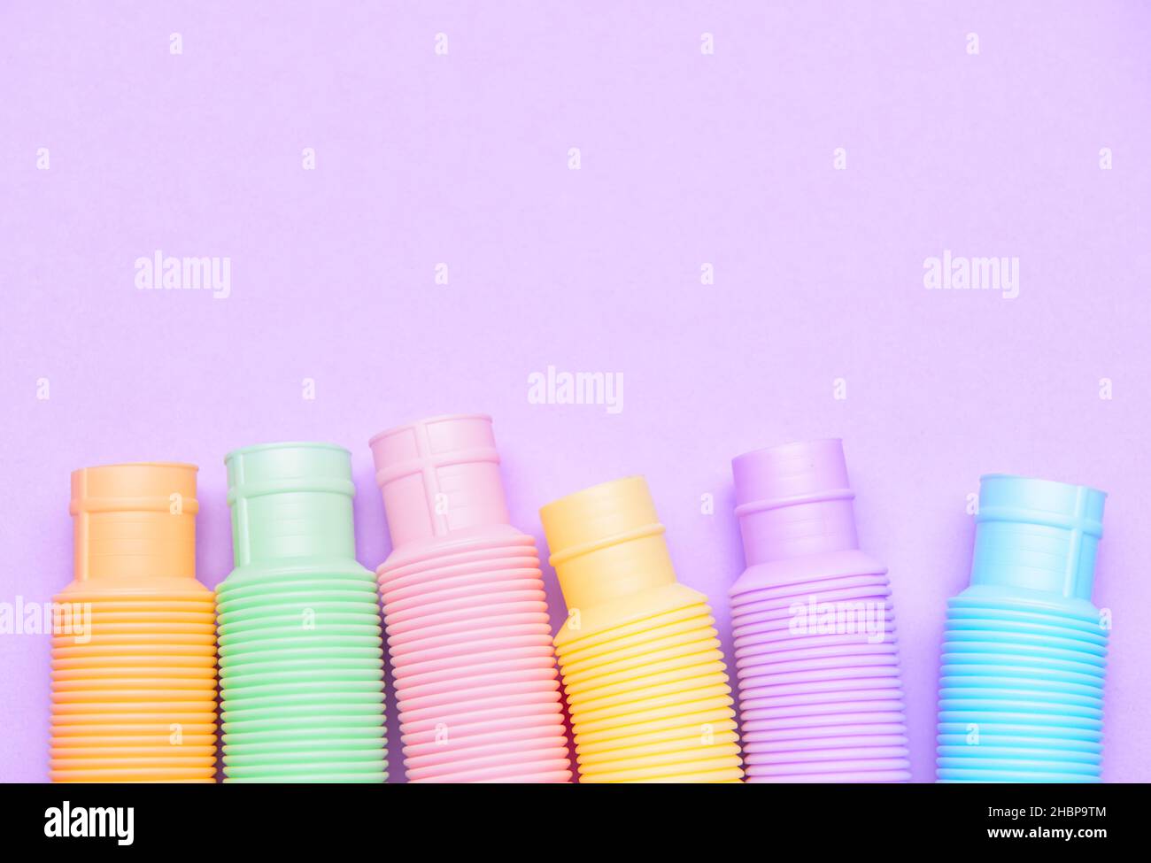 Different colorful Pop Tubes on purple background Stock Photo - Alamy