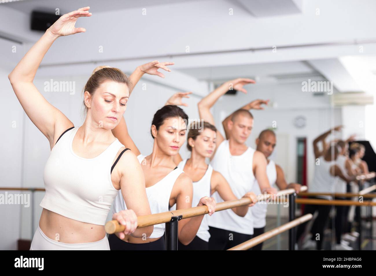 Group of people doing ballet exercises using barre in gym Stock Photo ...