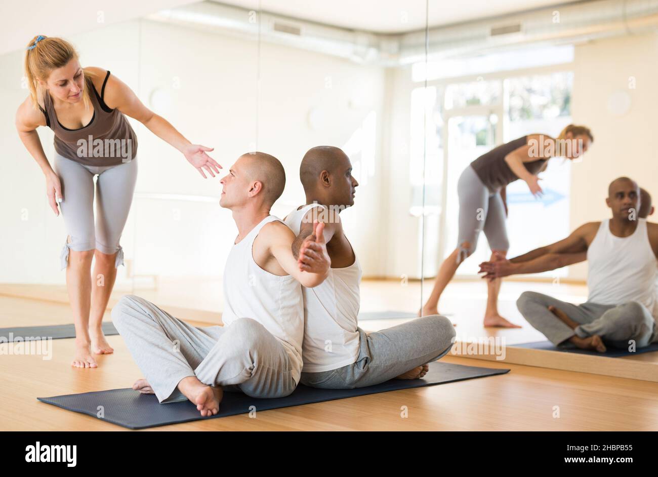 Yoga teacher helps couples learn yoga poses Stock Photo - Alamy